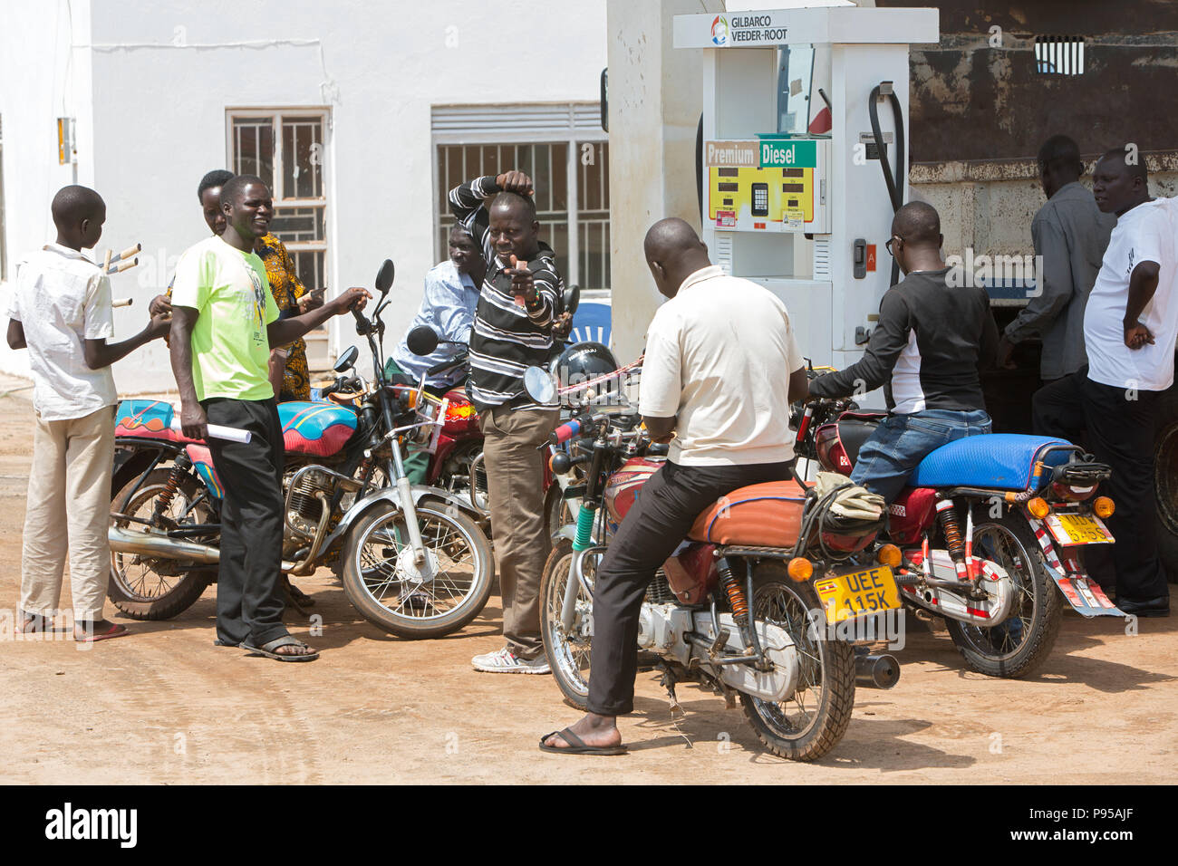 Kamdini, Uganda - street scene. Motorcyclists wait to be refueled at a ...