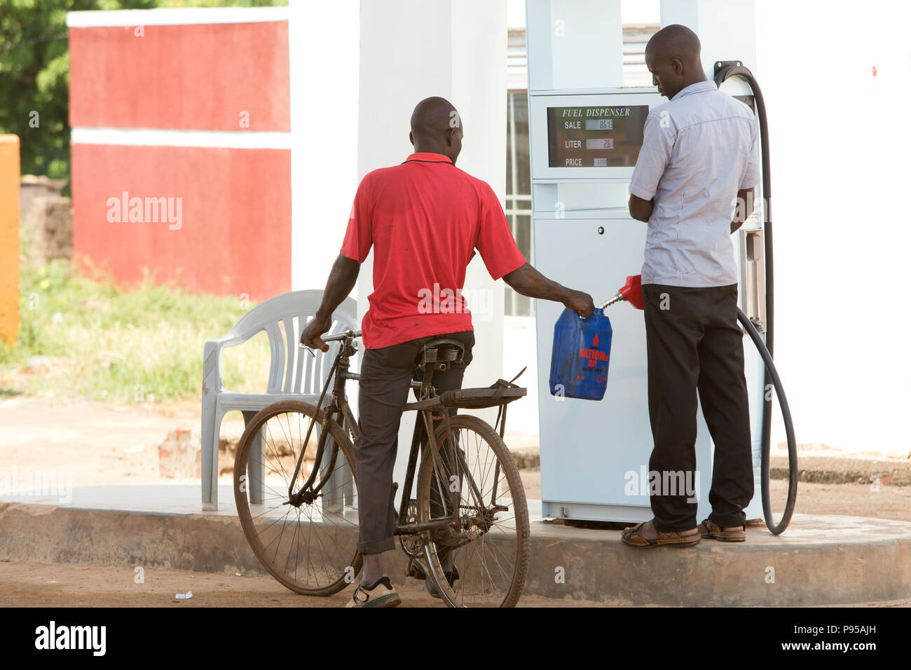 Kamdini, Uganda - street scene. A cyclist at a petrol pump at a petrol ...