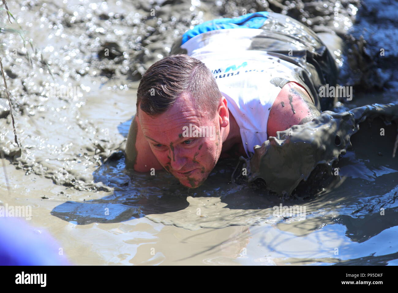 A man crawls through mud during a muddy obstacle event in Leeds Stock ...