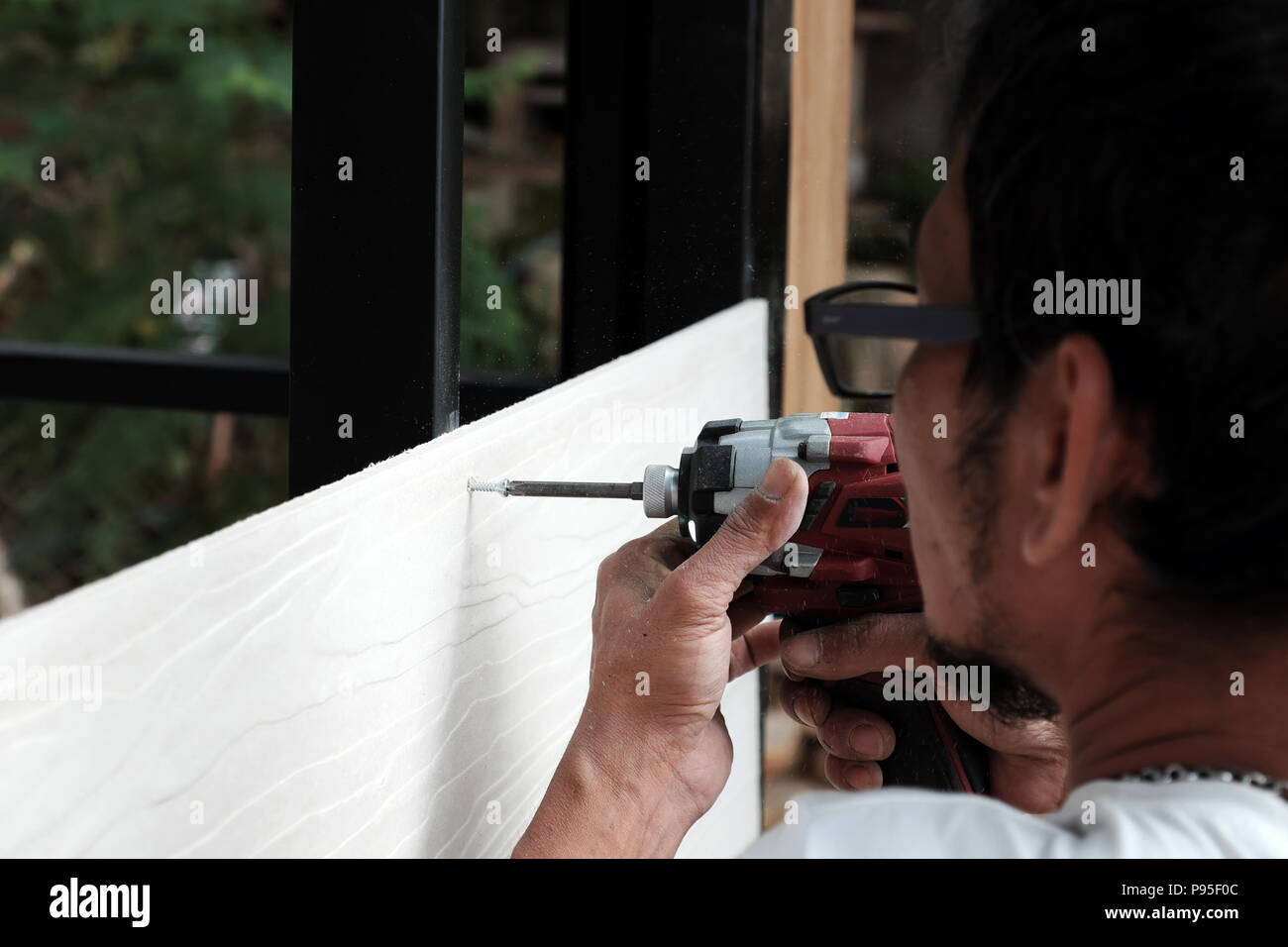 Vietnamese man work with hand drill drilling on wall to screw shot when ...