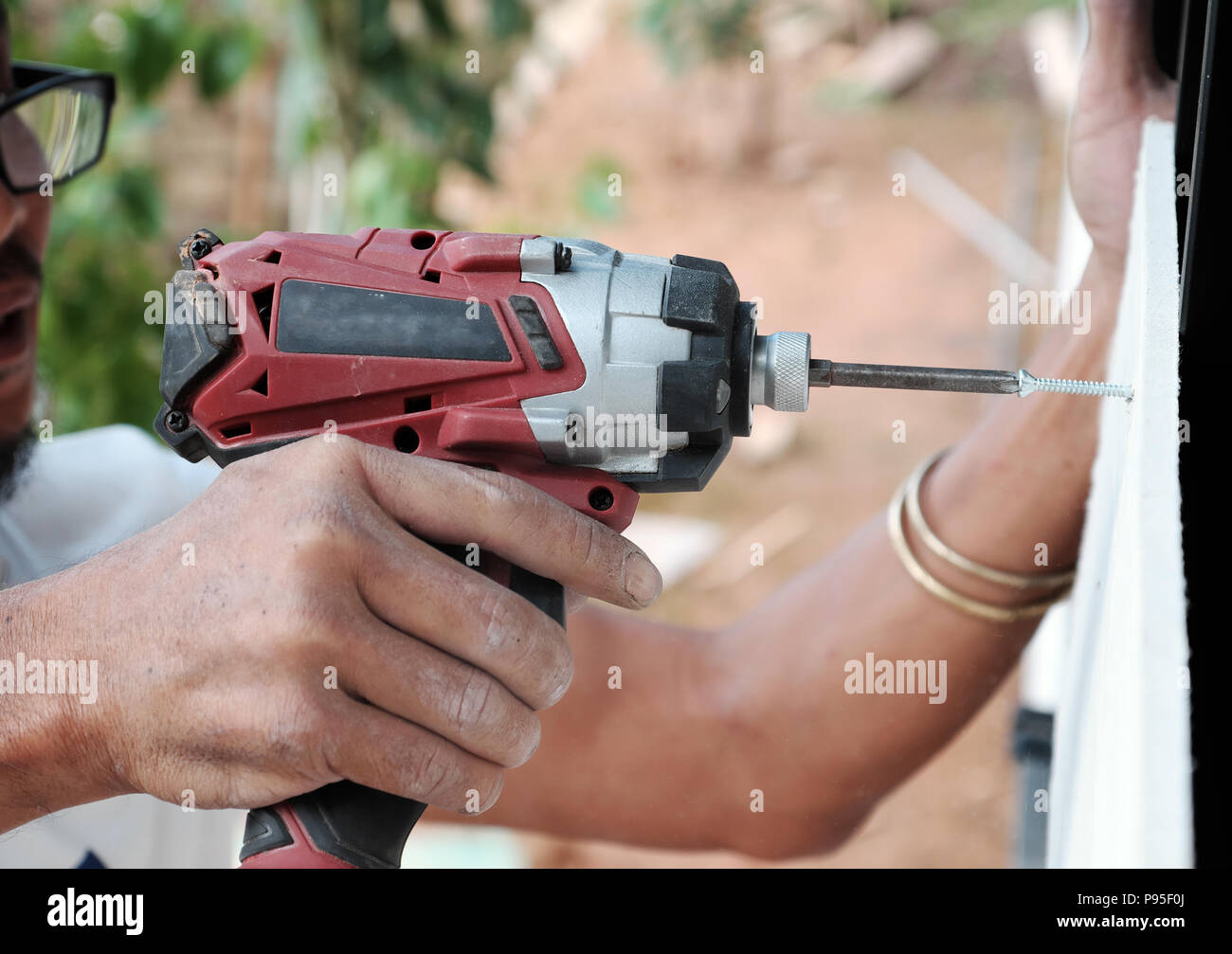 Vietnamese man work with hand drill drilling on wall to screw shot when ...