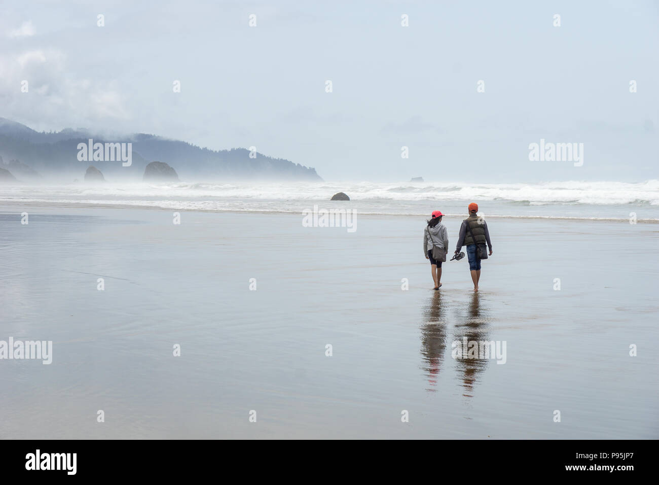 Couple walking on the beach on a dull oceanic weather, Cannon Beach ...