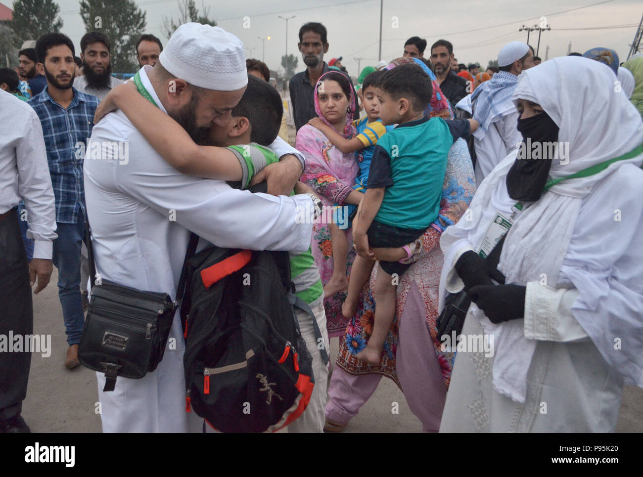 Srinagar, India. 14th July, 2018. A Hajj pilgrim hugs his son outside ...