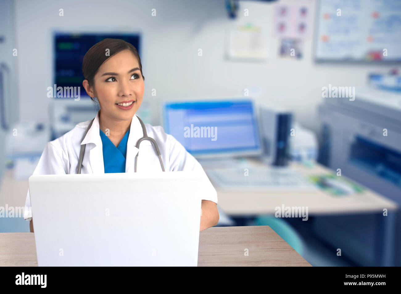Female doctor looking at something while working on her laptop computer ...