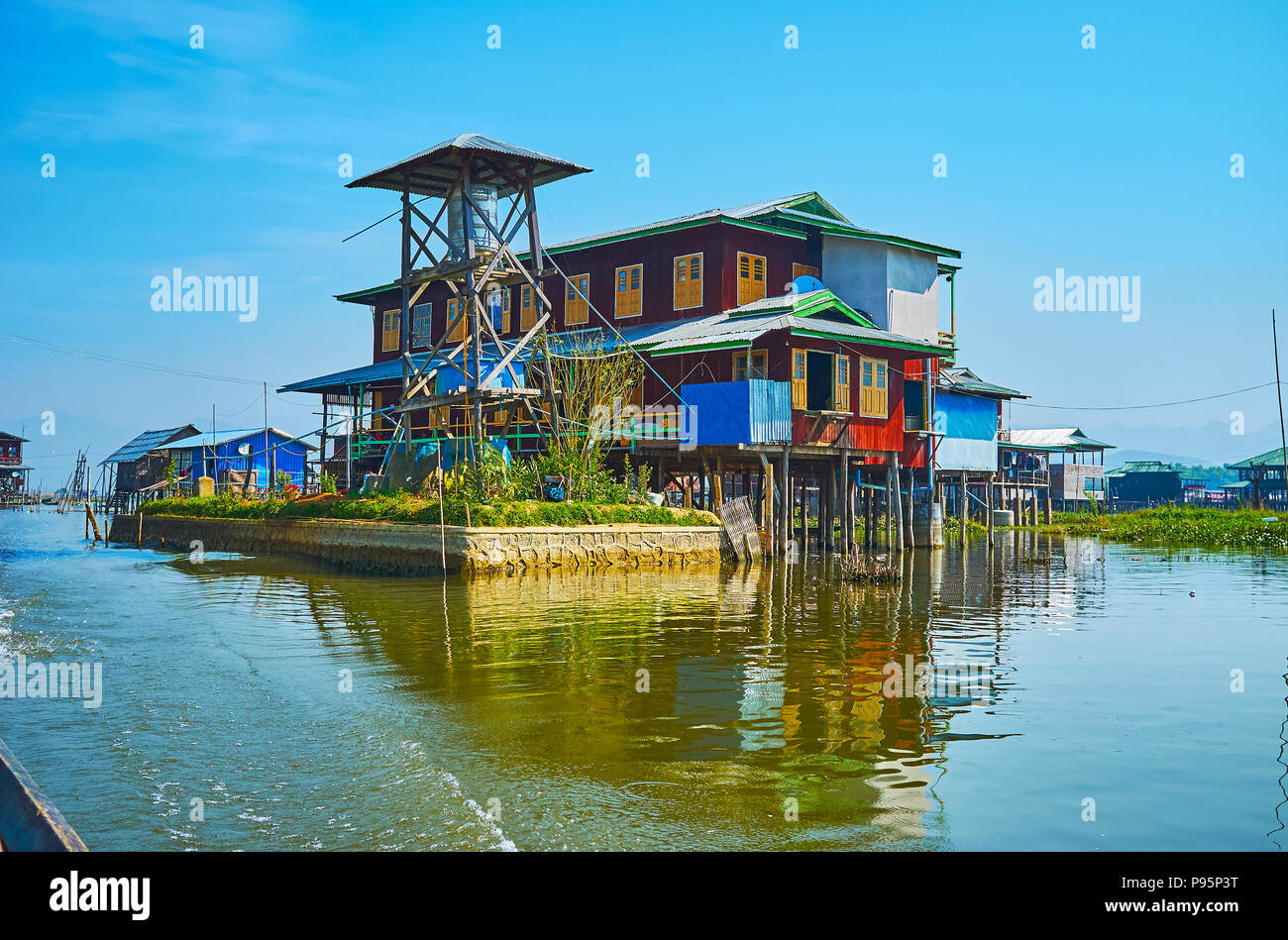 The primitive timber water tower next to the large house on stilts in ...