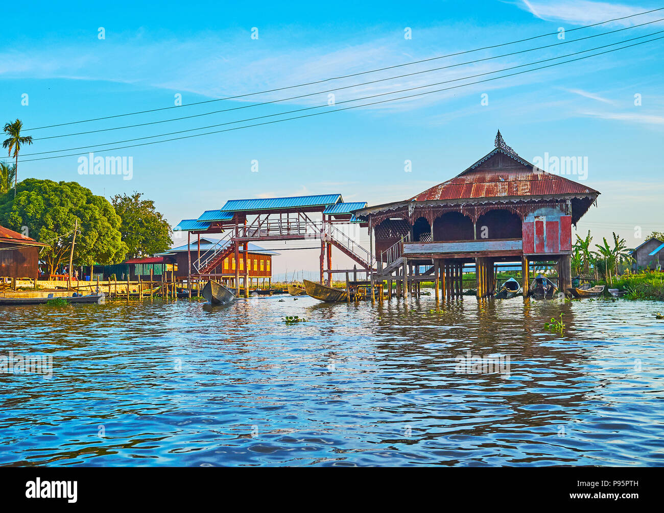 The old wooden stilt houses and scenic foot bridge with canoes, moored ...