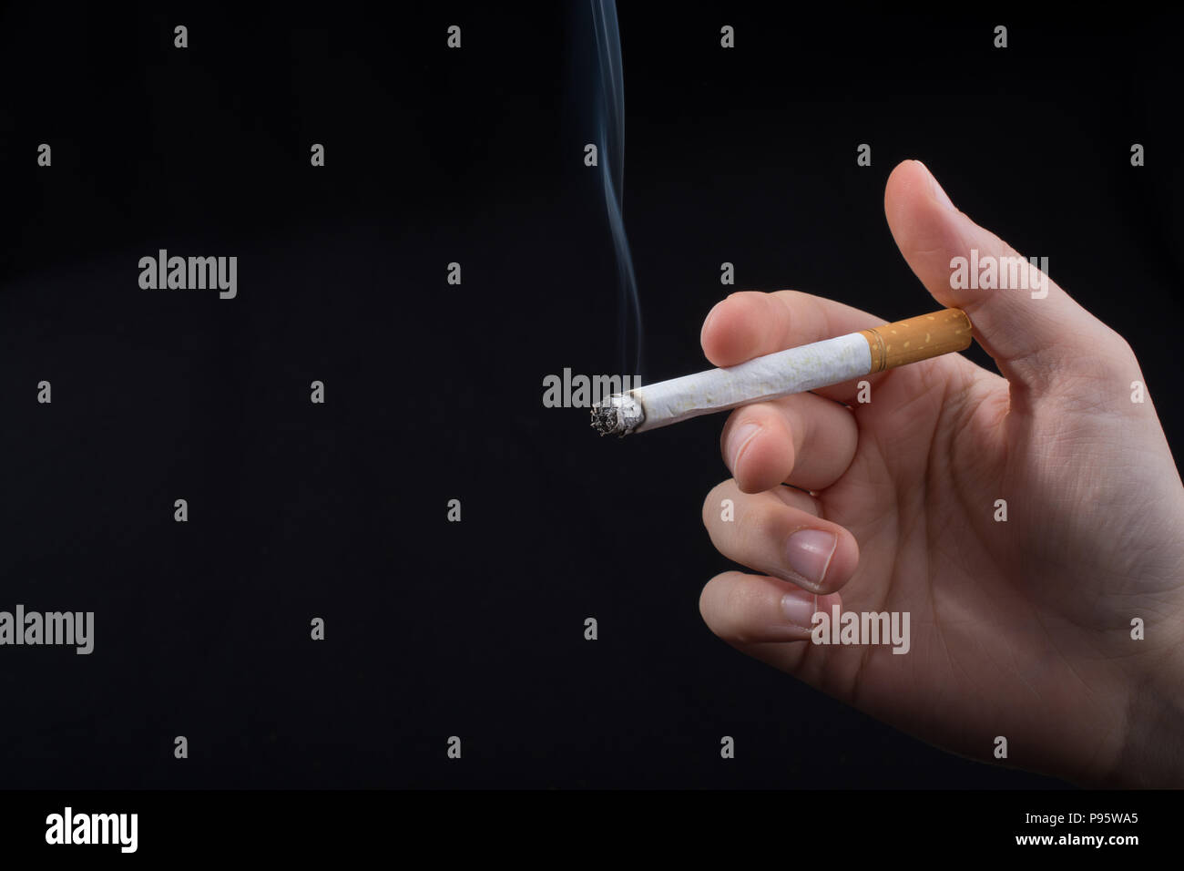 Hand is holding smoking cigarette with smoke around Stock Photo - Alamy