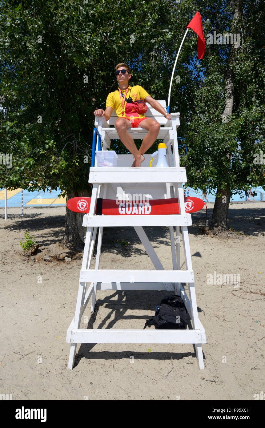 Lifeguard sitting at his observation post on a beach and watching ...