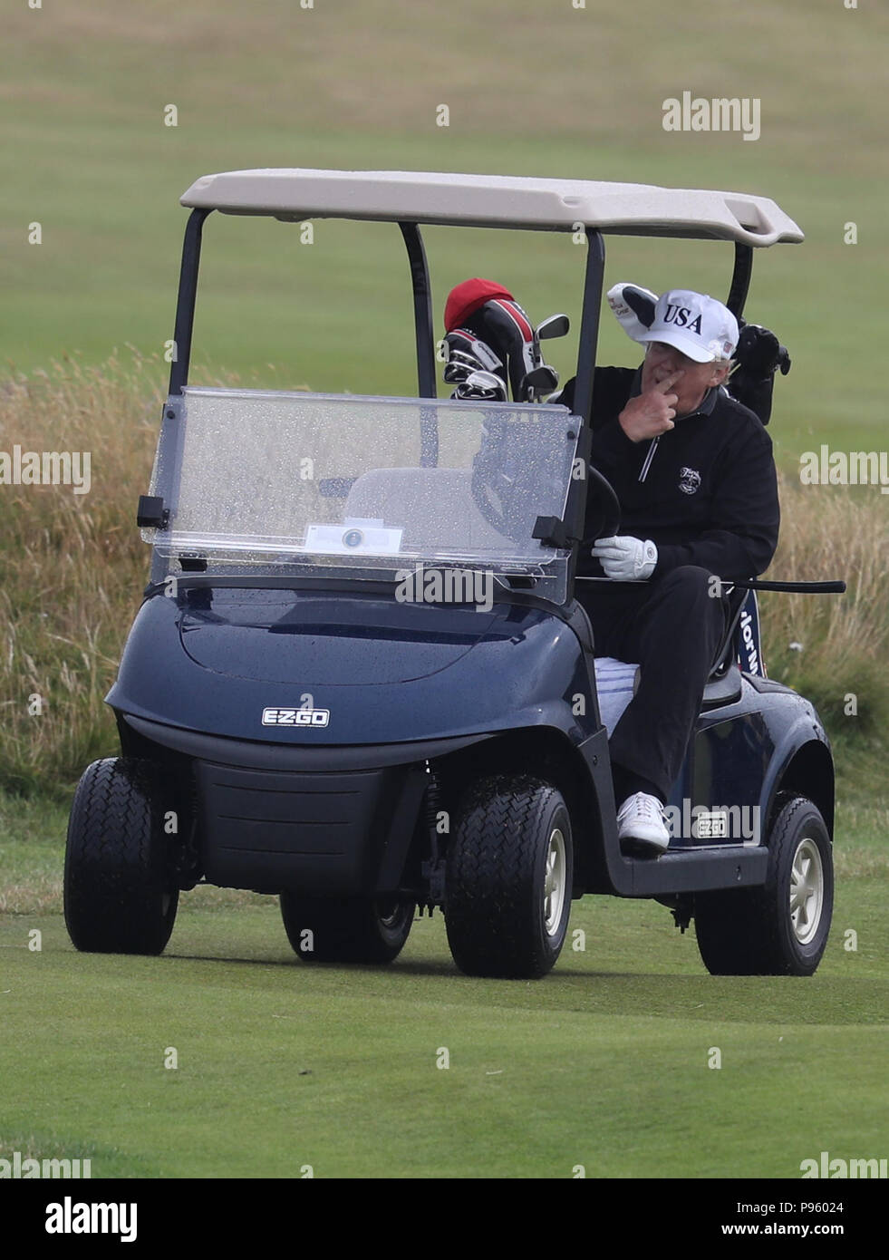 US President Donald Trump drives a golf buggy on his golf course at the ...