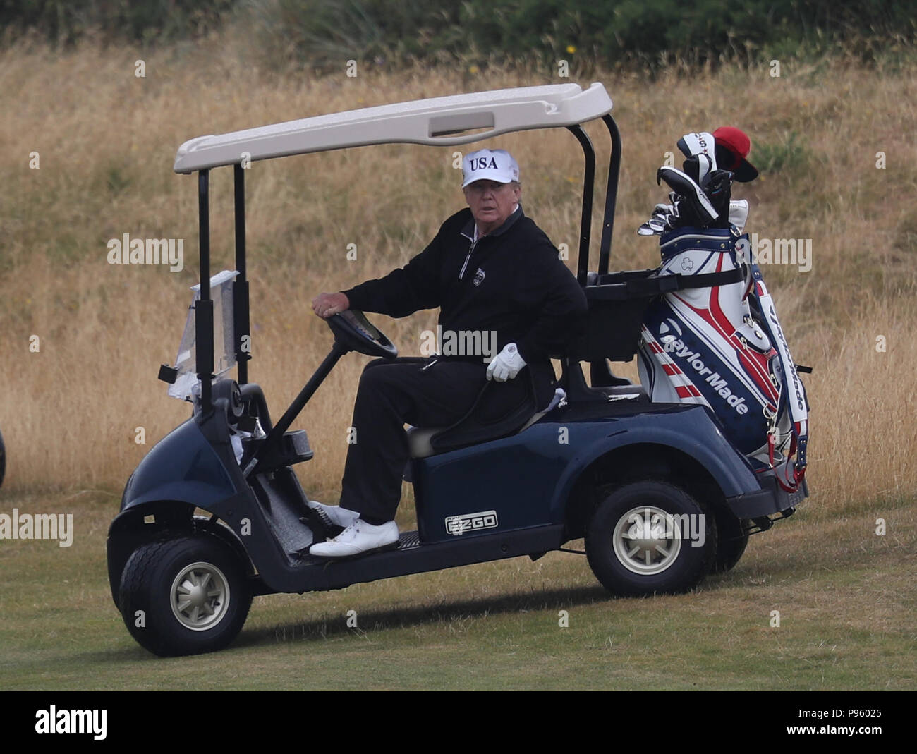 US President Donald Trump drives a golf buggy on his golf course at the ...