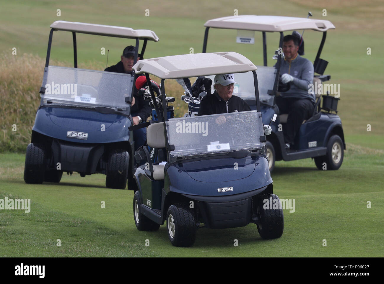 US President Donald Trump drives a golf buggy on his golf course at the ...