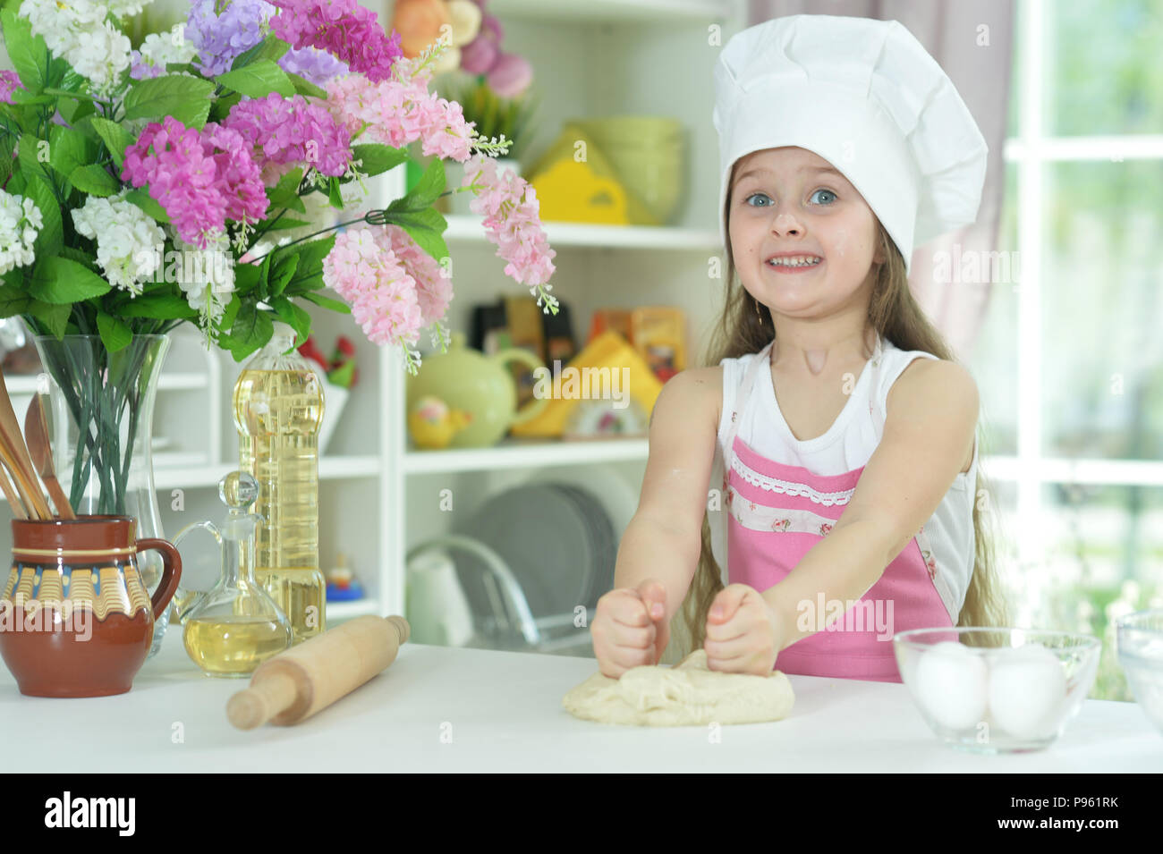 Cute girl in chefs hat making dough in the kitchen at home Stock Photo ...