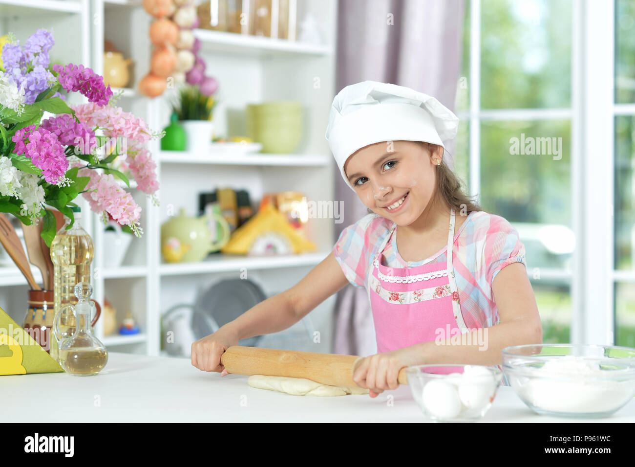 Cute little girl making dinner on kitchen table at home Stock Photo - Alamy