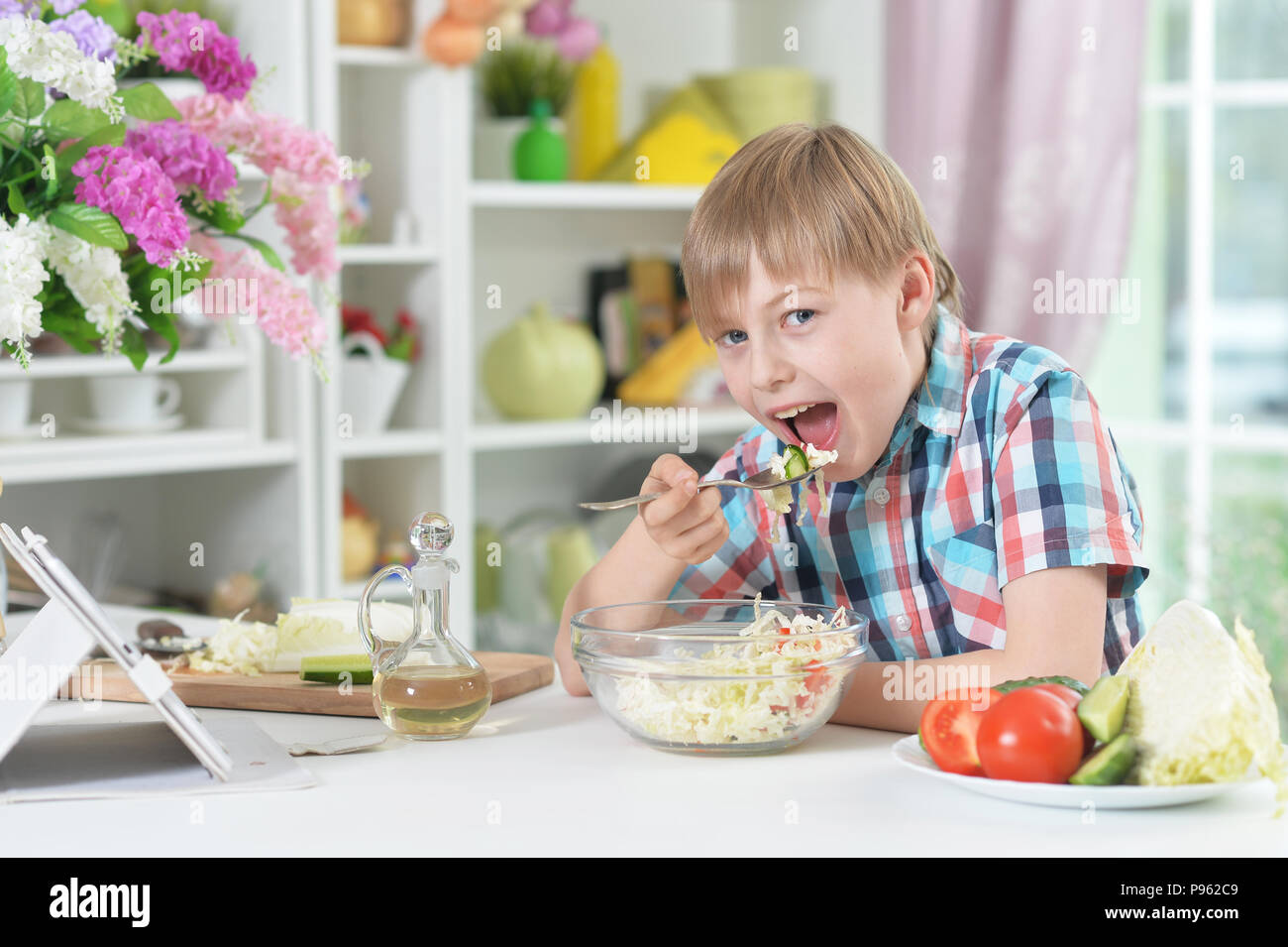 Cute boy eating healthy salad at kitchen table Stock Photo - Alamy