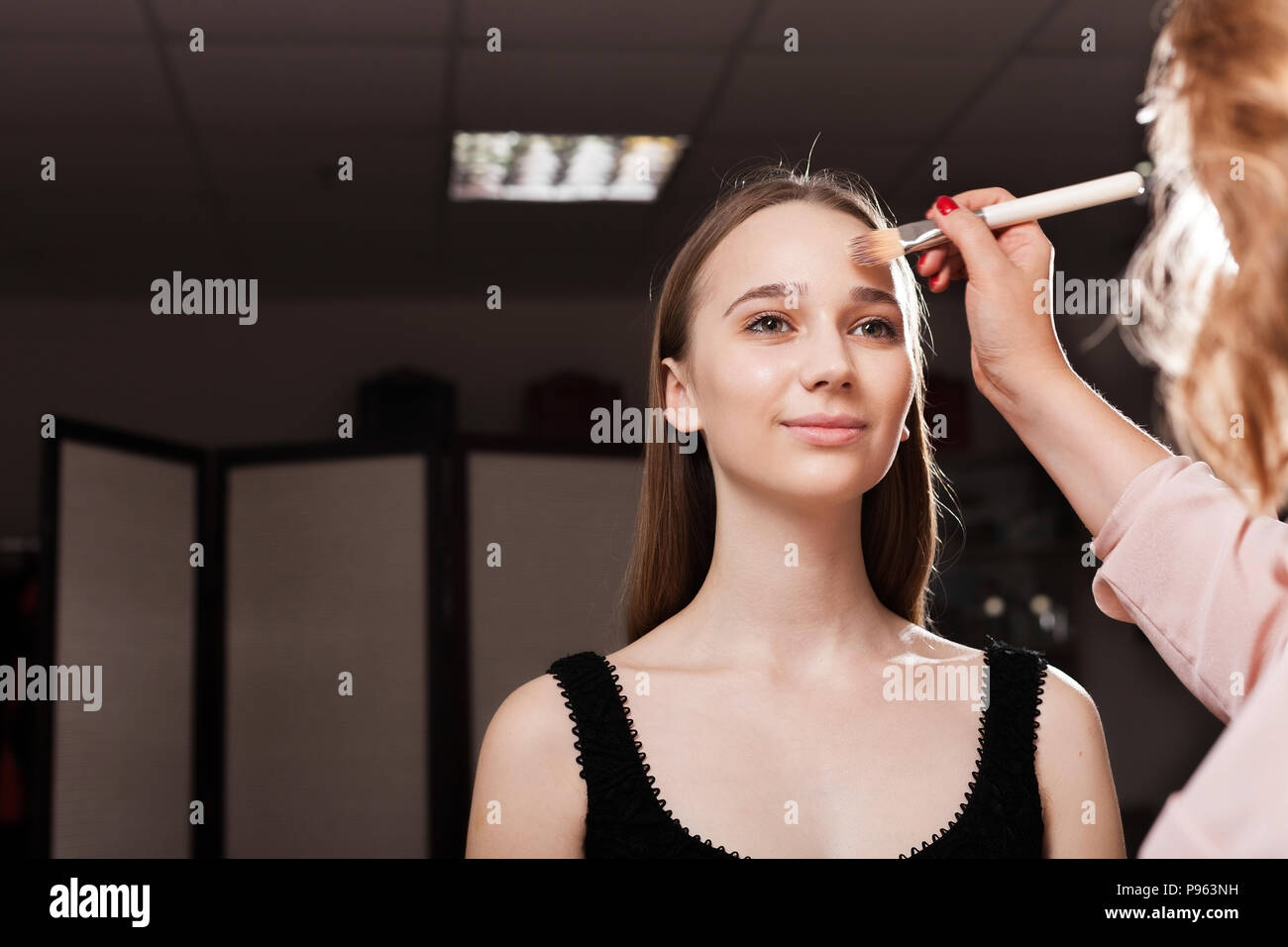 makeup artist applying foundation on a forehead of a girl Stock Photo ...