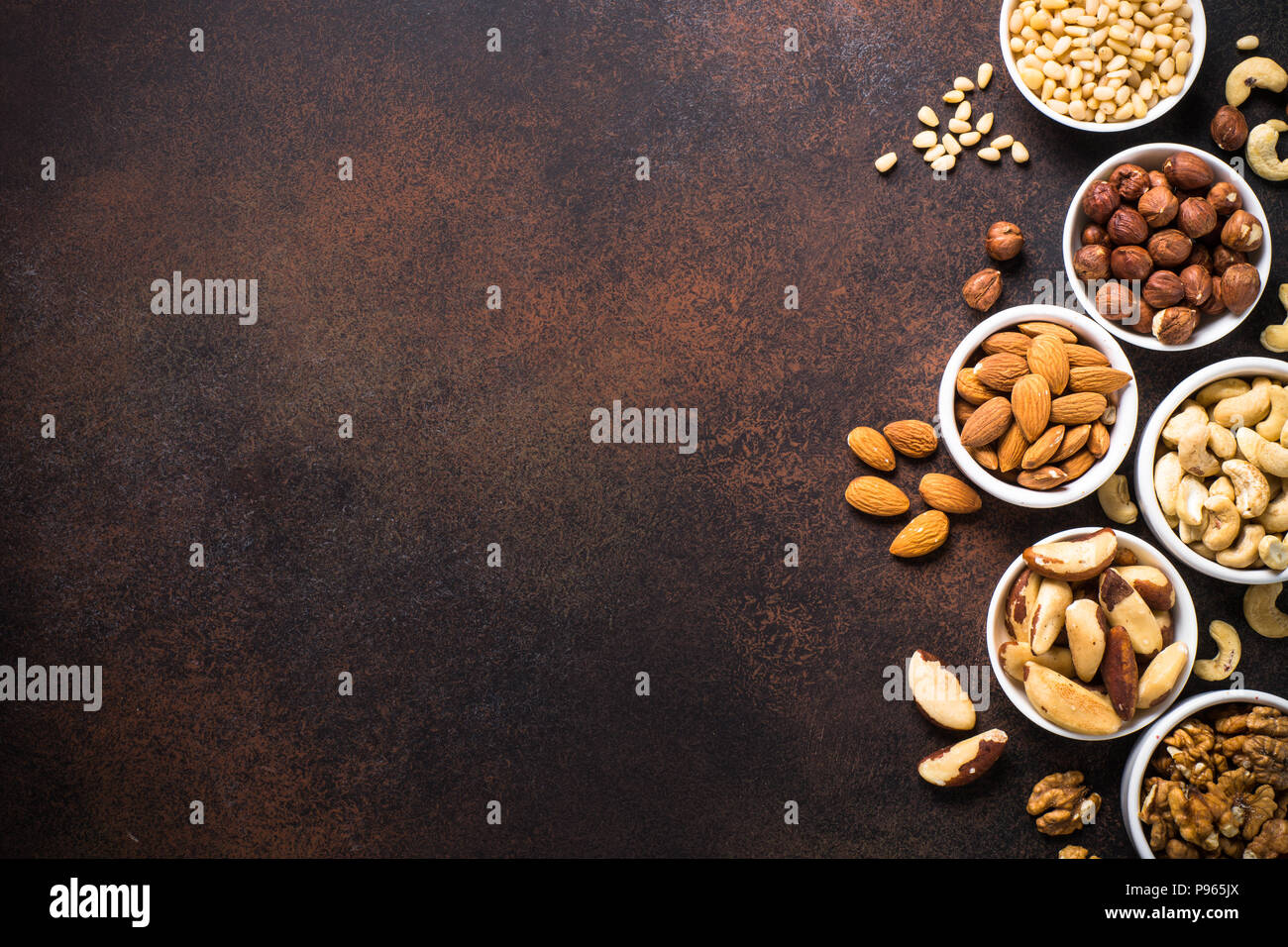 Assortment of nuts in bowls on dark stone table. Cashew, hazelnuts ...