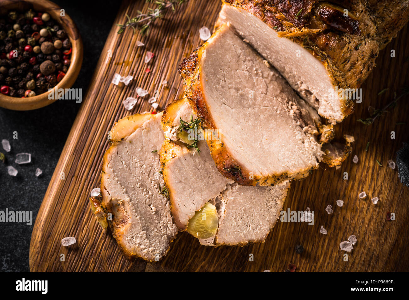 Roast pork meat with herbs and spices on black stone table. Top view ...