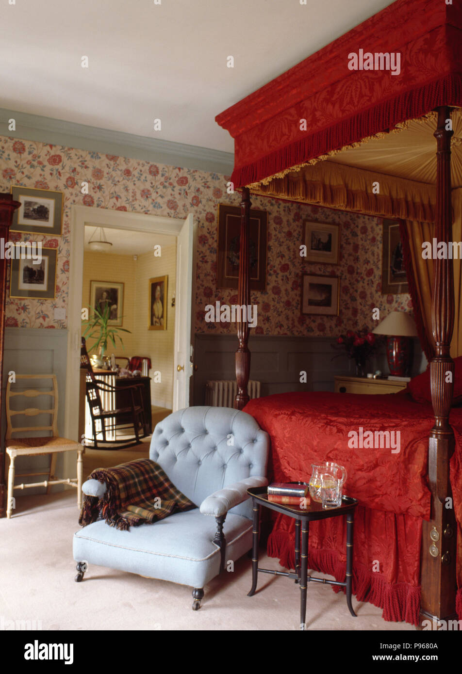 Red silk canopy and cover on antique four-poster bed in country bedroom ...