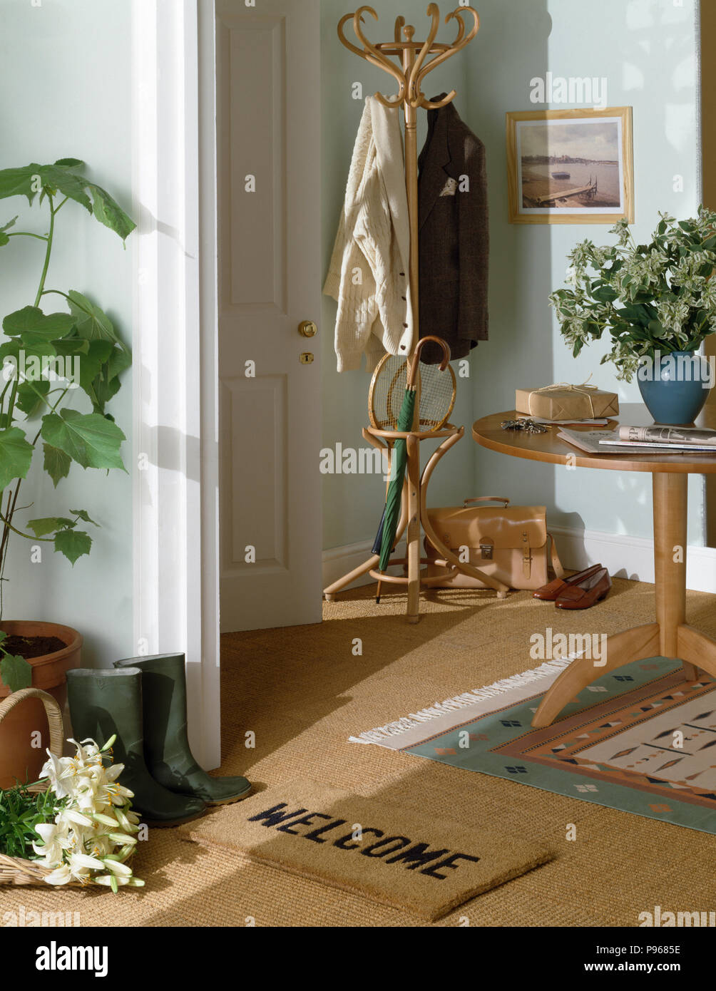 Clothes on bentwood stand in hall with welcome mat and sisal carpet ...