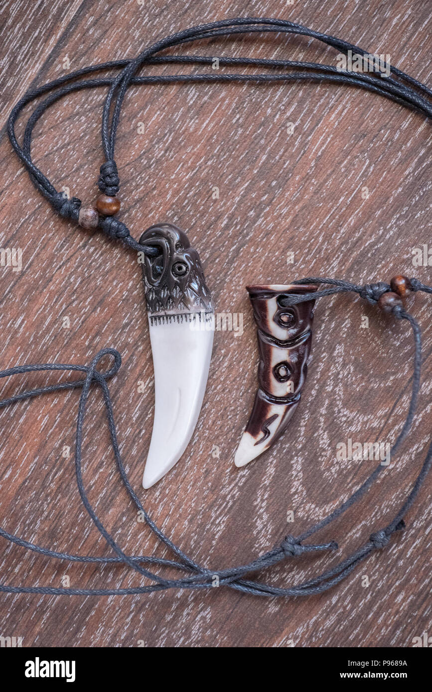 Big bear tooth and bone pendants carved from siberian deer on a brown ...