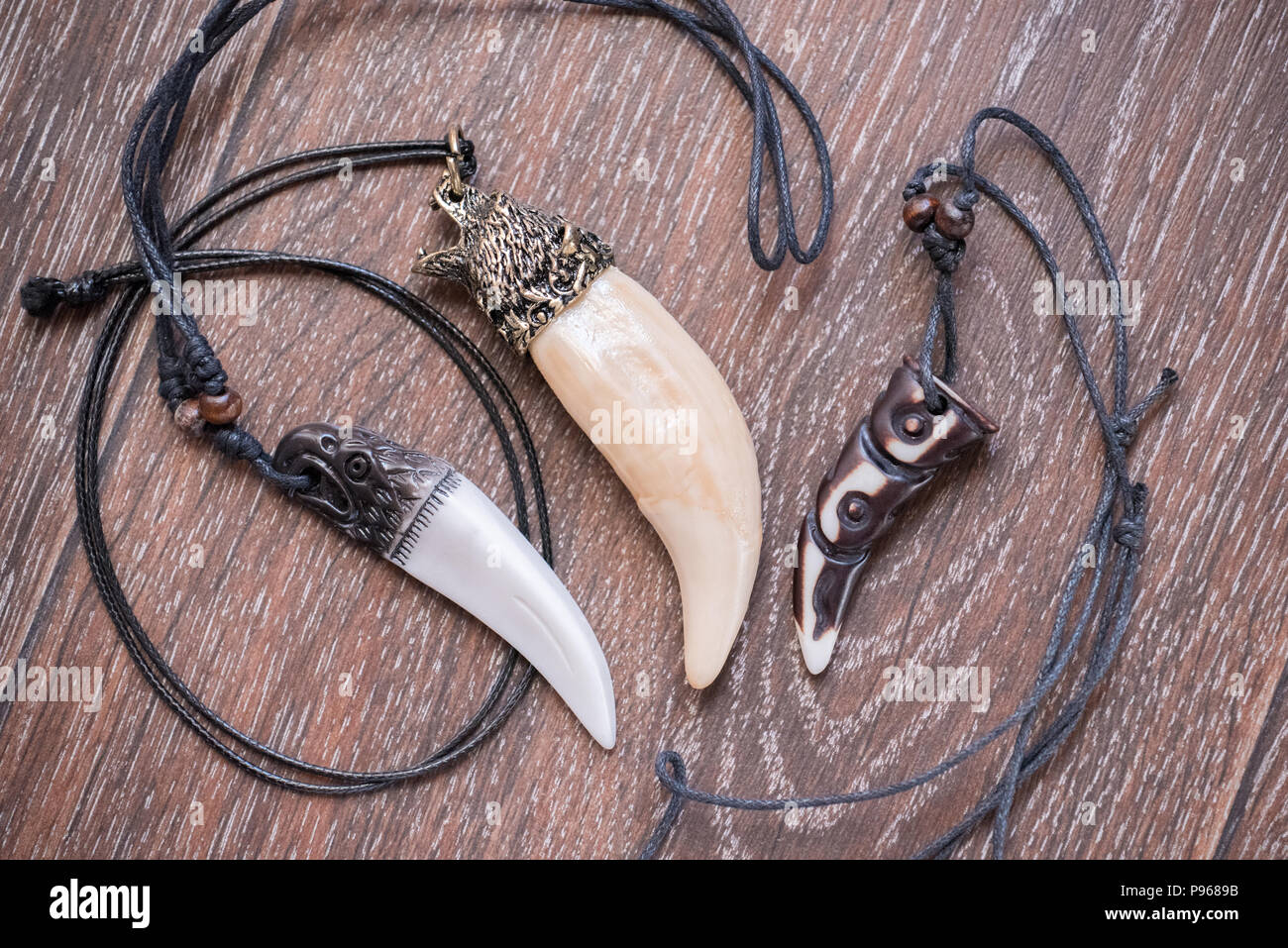 Big bear tooth and bone pendants carved from siberian deer on a brown ...