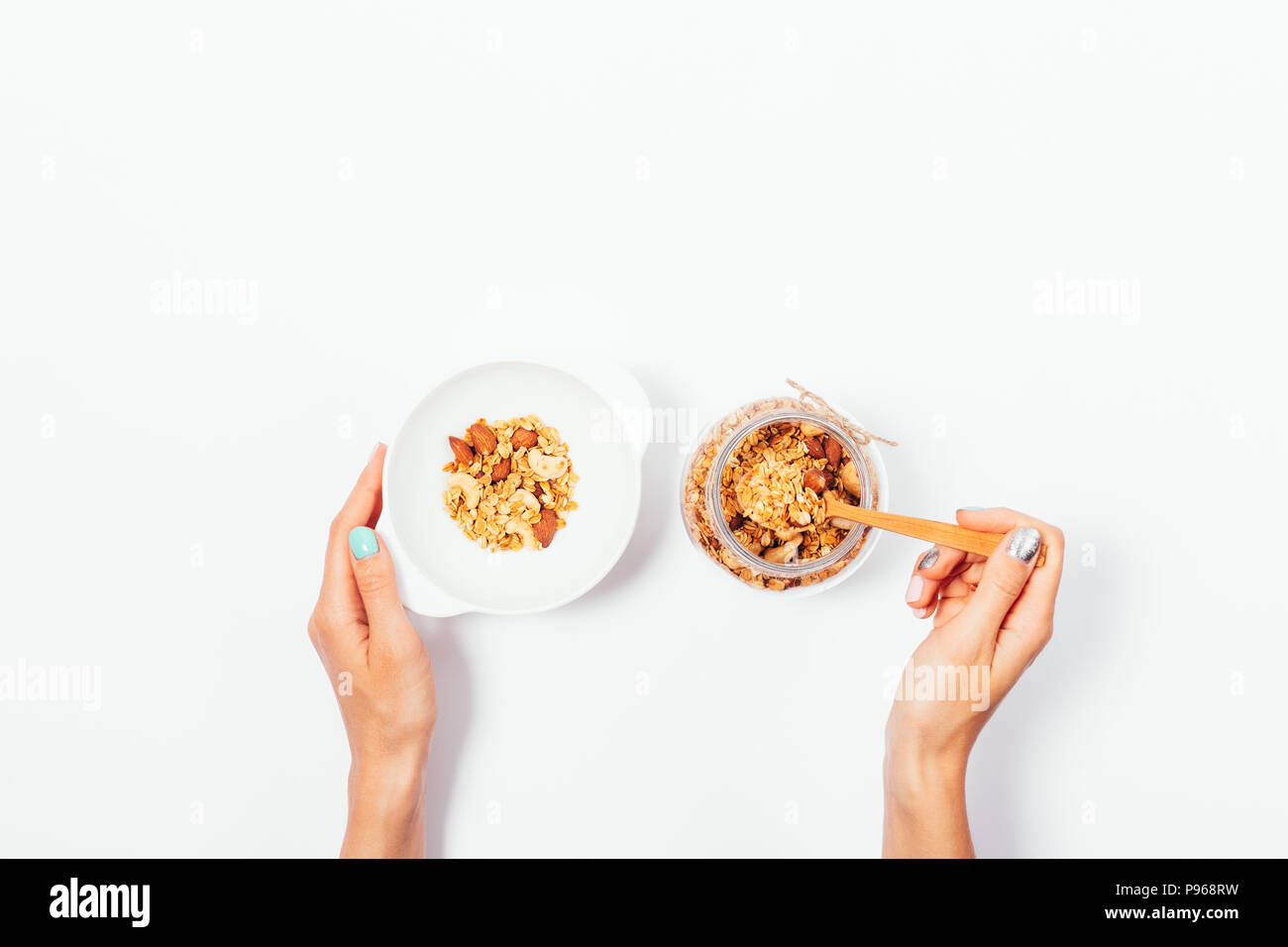 Woman doing healthy granola meal, top view. Female's hands holding ...