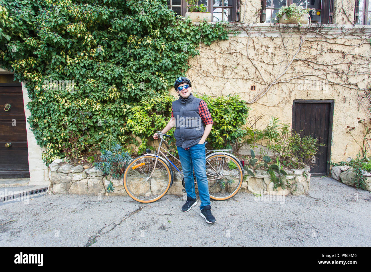 Handsome guy cyclist in cycling clothes and helmet posing near bicycle ...