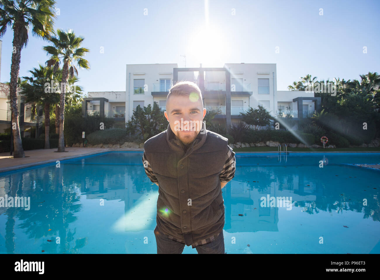Man posing against pool background putting his hands behind his back ...
