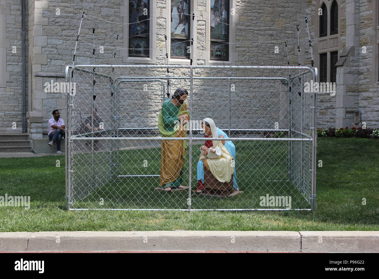 The Holy Family, Jesus, Mary, and Joseph are caged behind a barbed wire ...