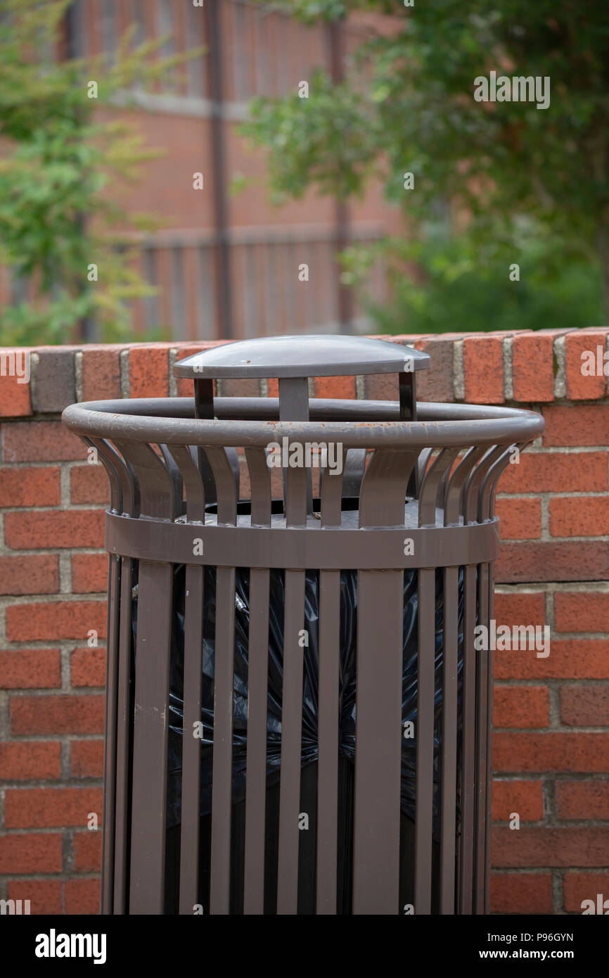 Large, round public garbage can against a red brick wall Stock Photo ...