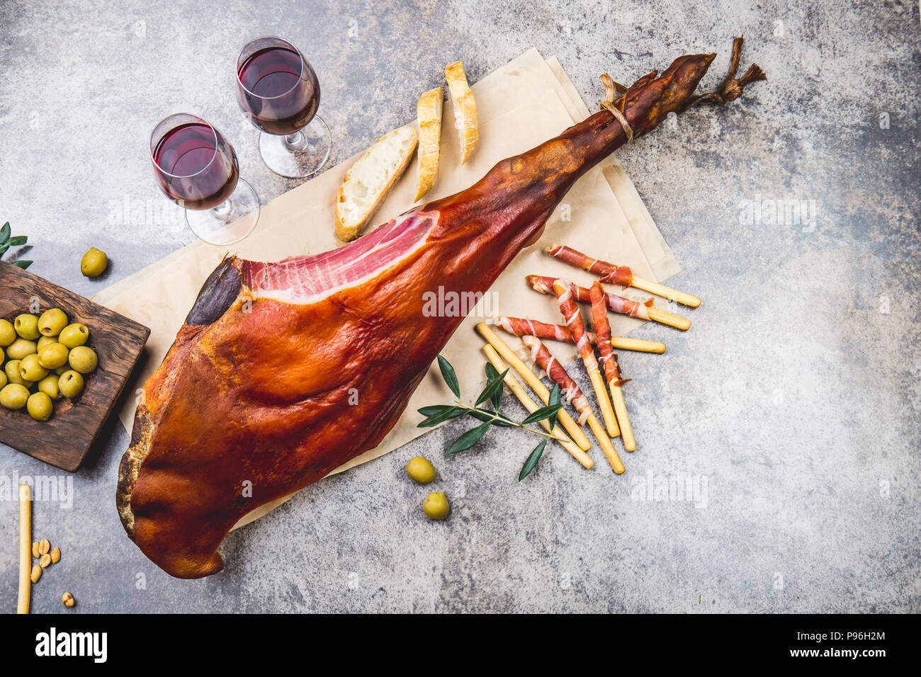 Whole leg HAM JAMON SERRANO and red wine on gray background. Top view ...