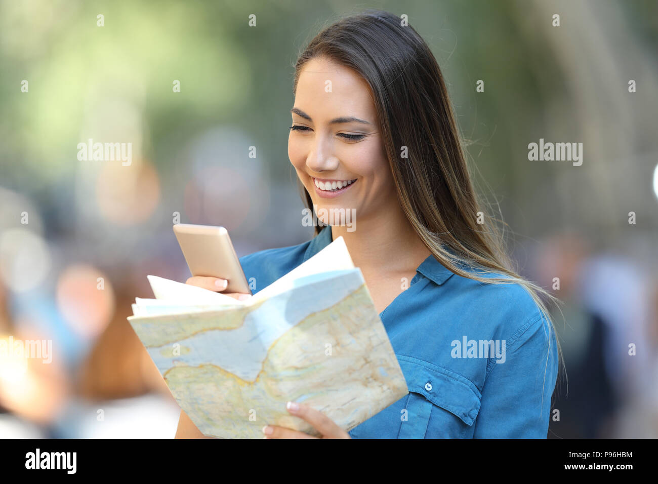 Tourist checking destination in a smart phone and a paper map in the ...
