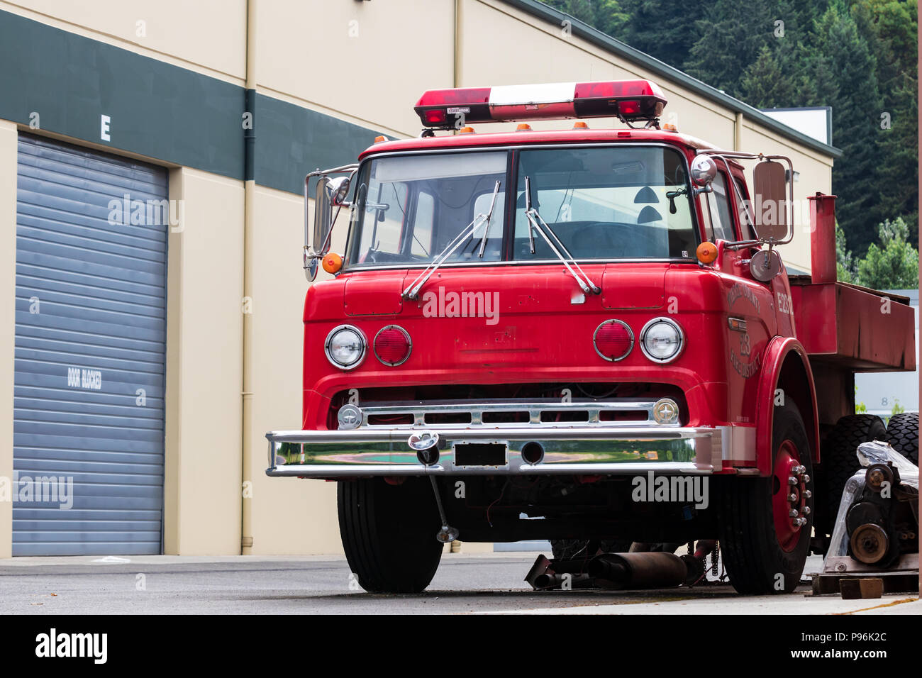 Old red dismantled fire engine parked in an industrial complex with tan ...