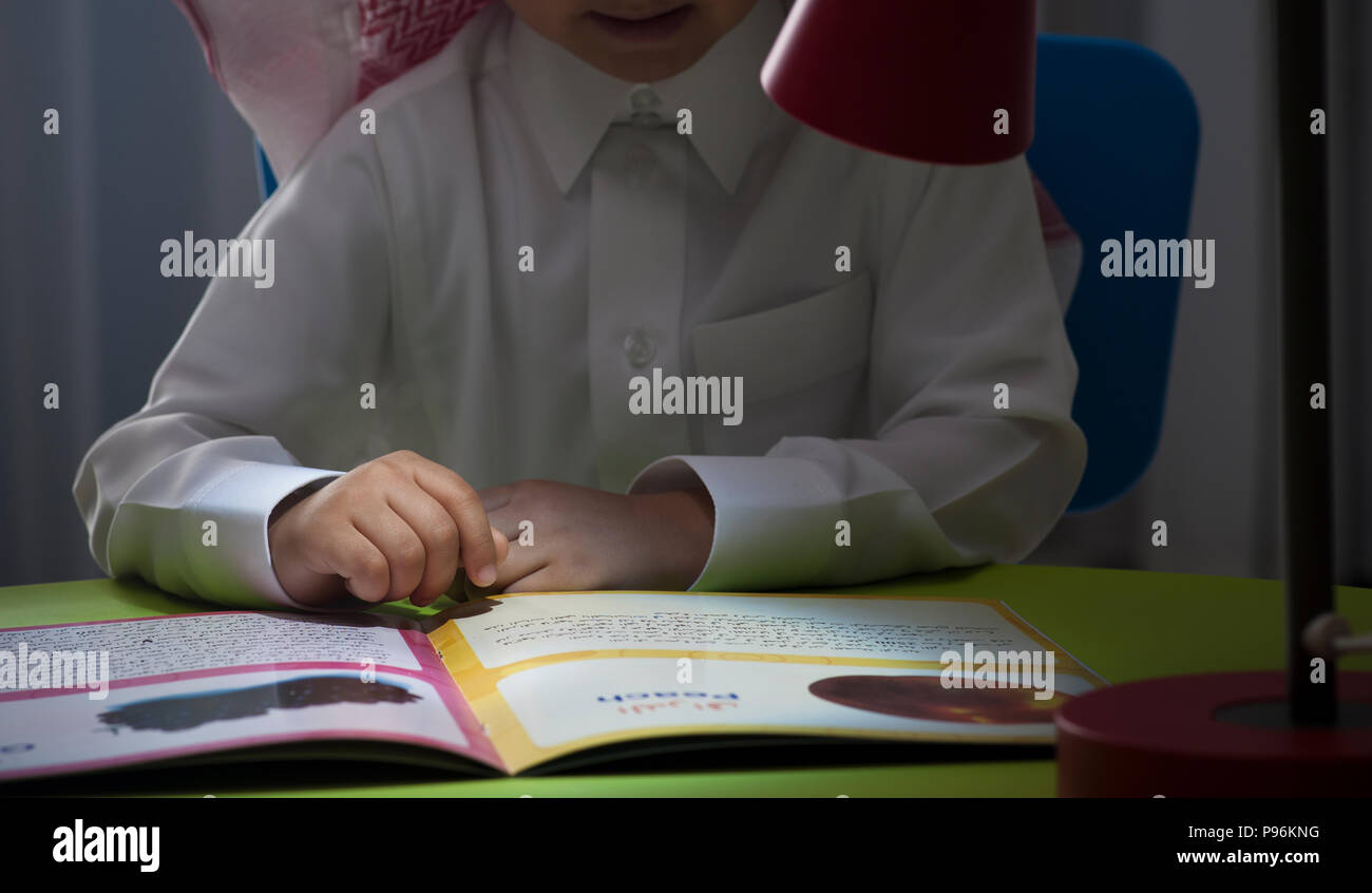 Saudi boy reading a story at a table with lamp close up Stock Photo - Alamy