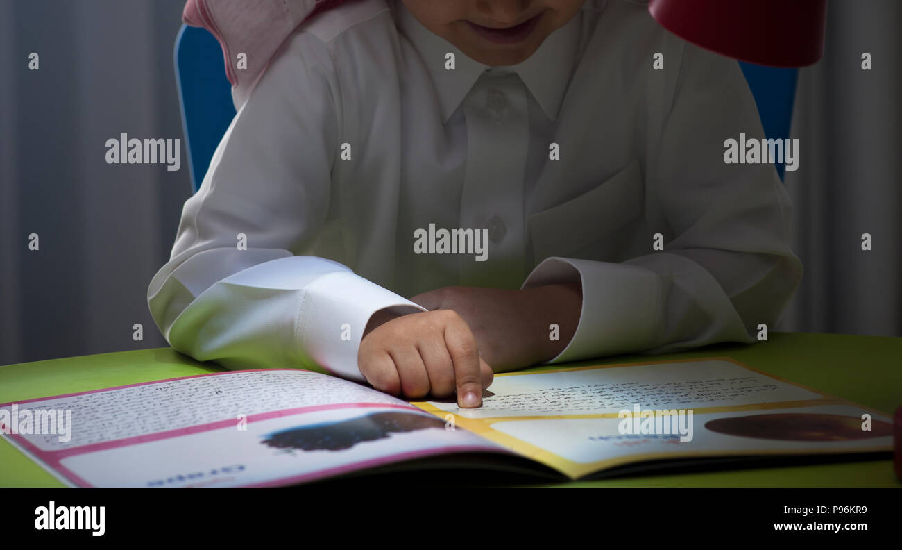 Saudi boy reading a story at a table with lamp close up Stock Photo - Alamy