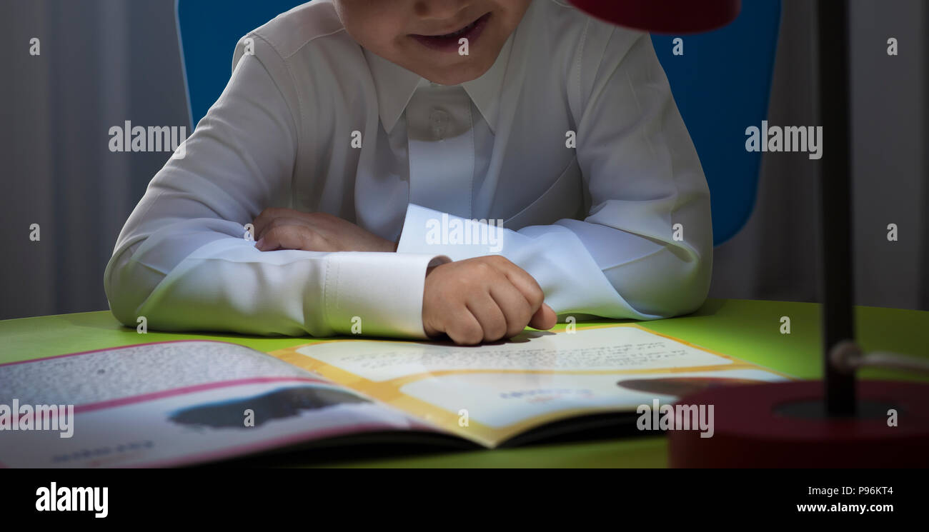 Boy reading a story at a table with lamp close up Stock Photo - Alamy