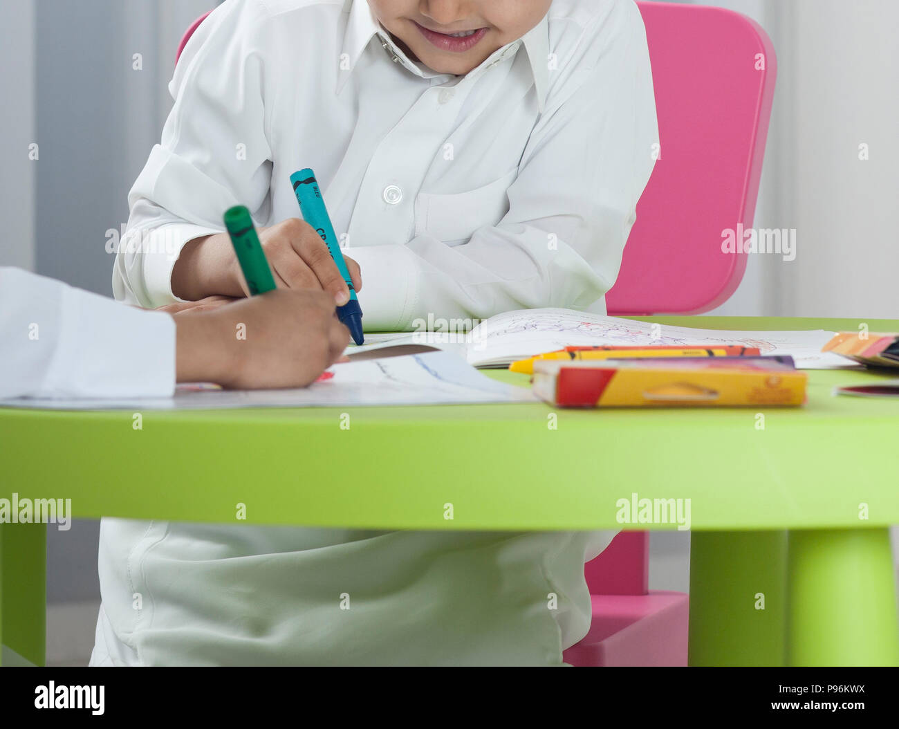 Kids drawing with colored crayons on paper at a table Stock Photo - Alamy