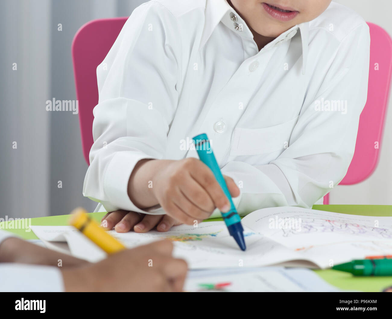 Kids drawing with colored crayons on paper at a table Stock Photo - Alamy