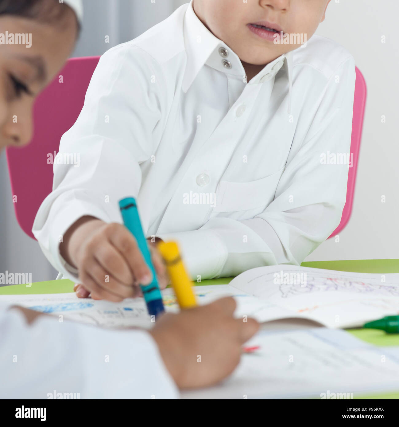 Kids drawing with colored crayons on paper at a table Stock Photo - Alamy
