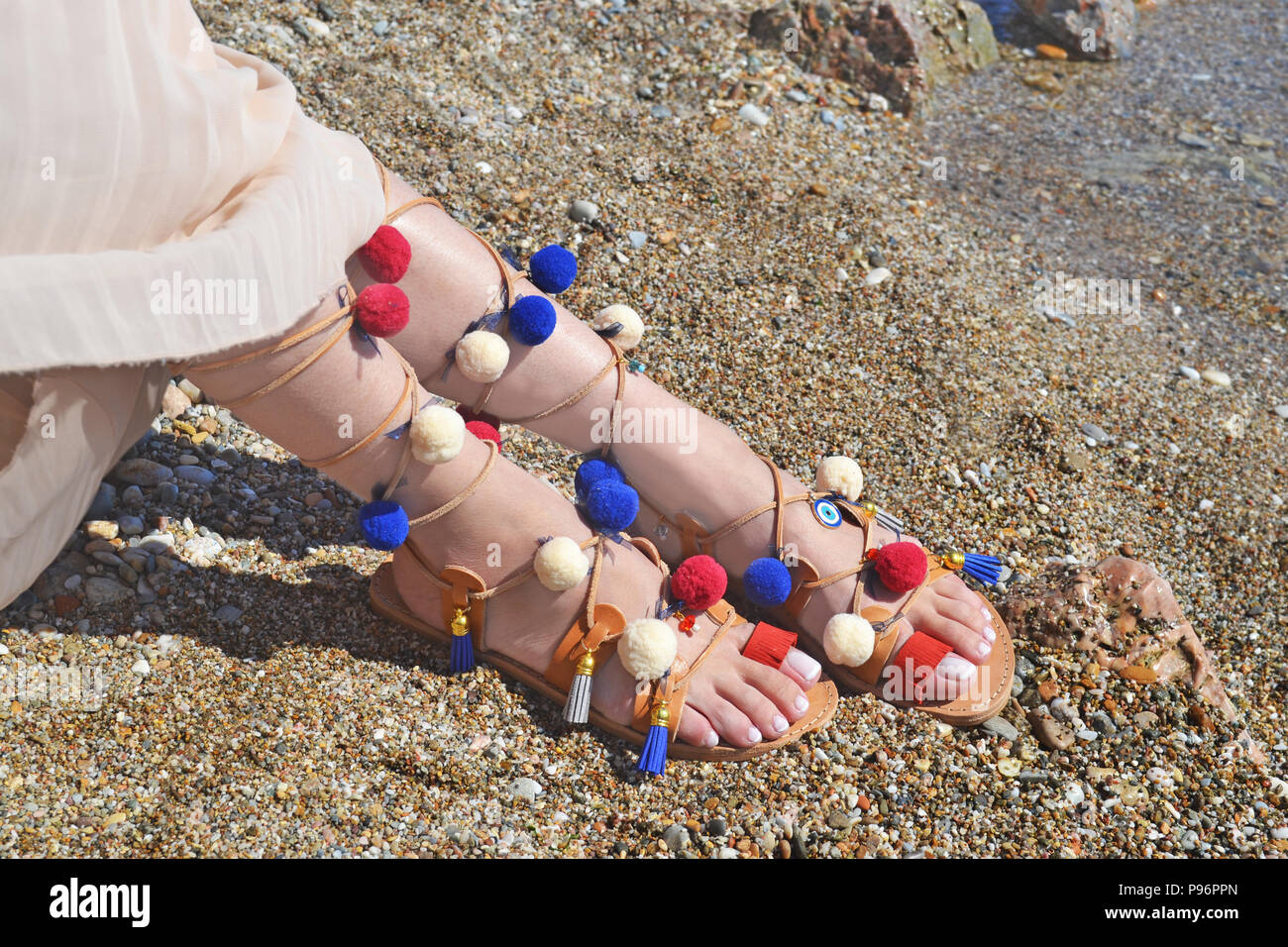 bohemian greek sandals with colorful pom pom advertisement on the beach ...