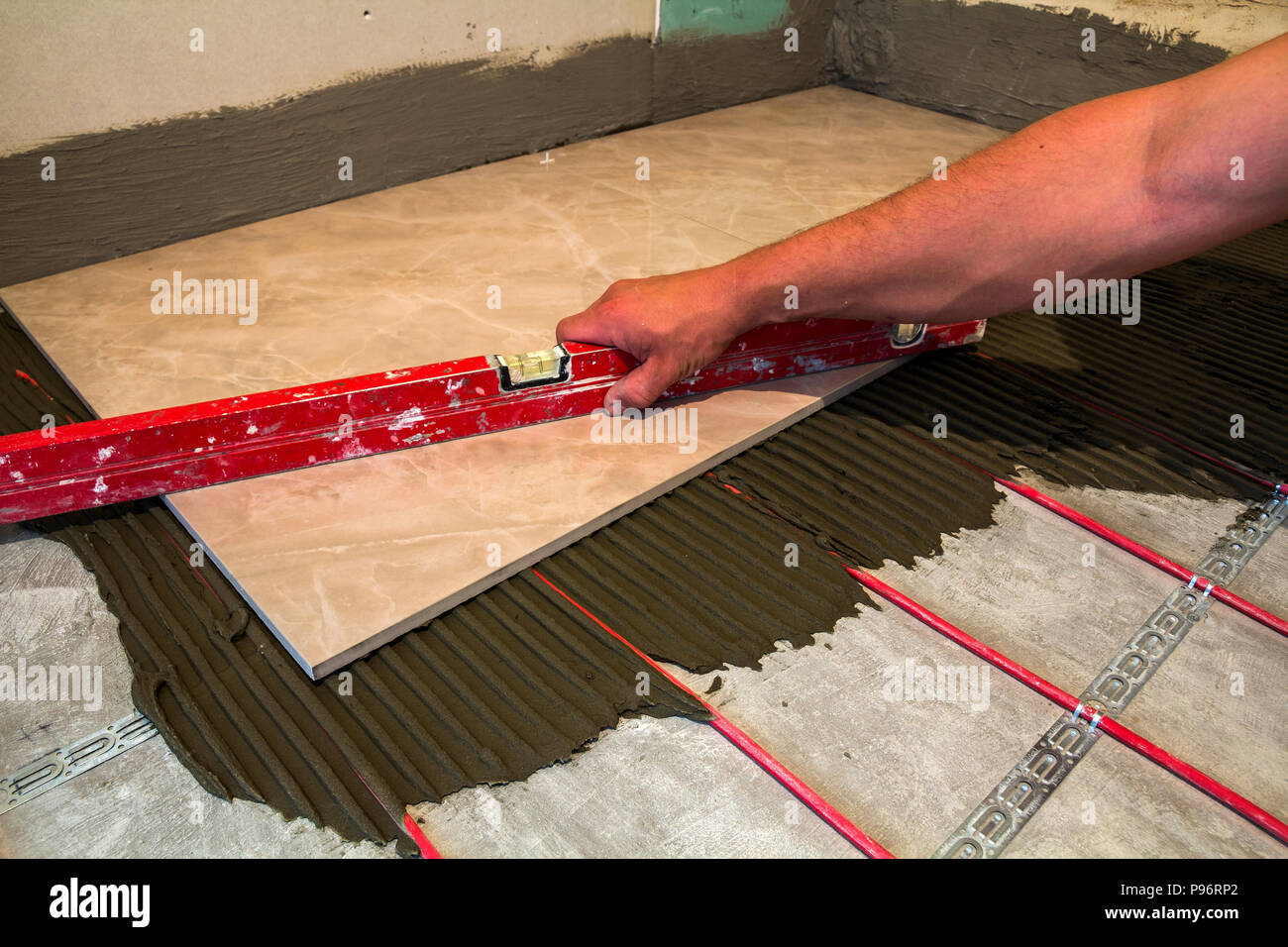 Ceramic tiles and tools for tiler. Worker hand installing floor tiles. Home improvement ...