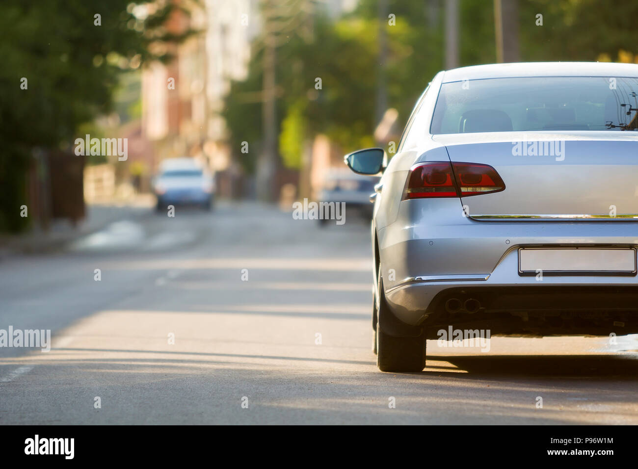 Close-up back view of new shiny expensive silver car moving along city ...