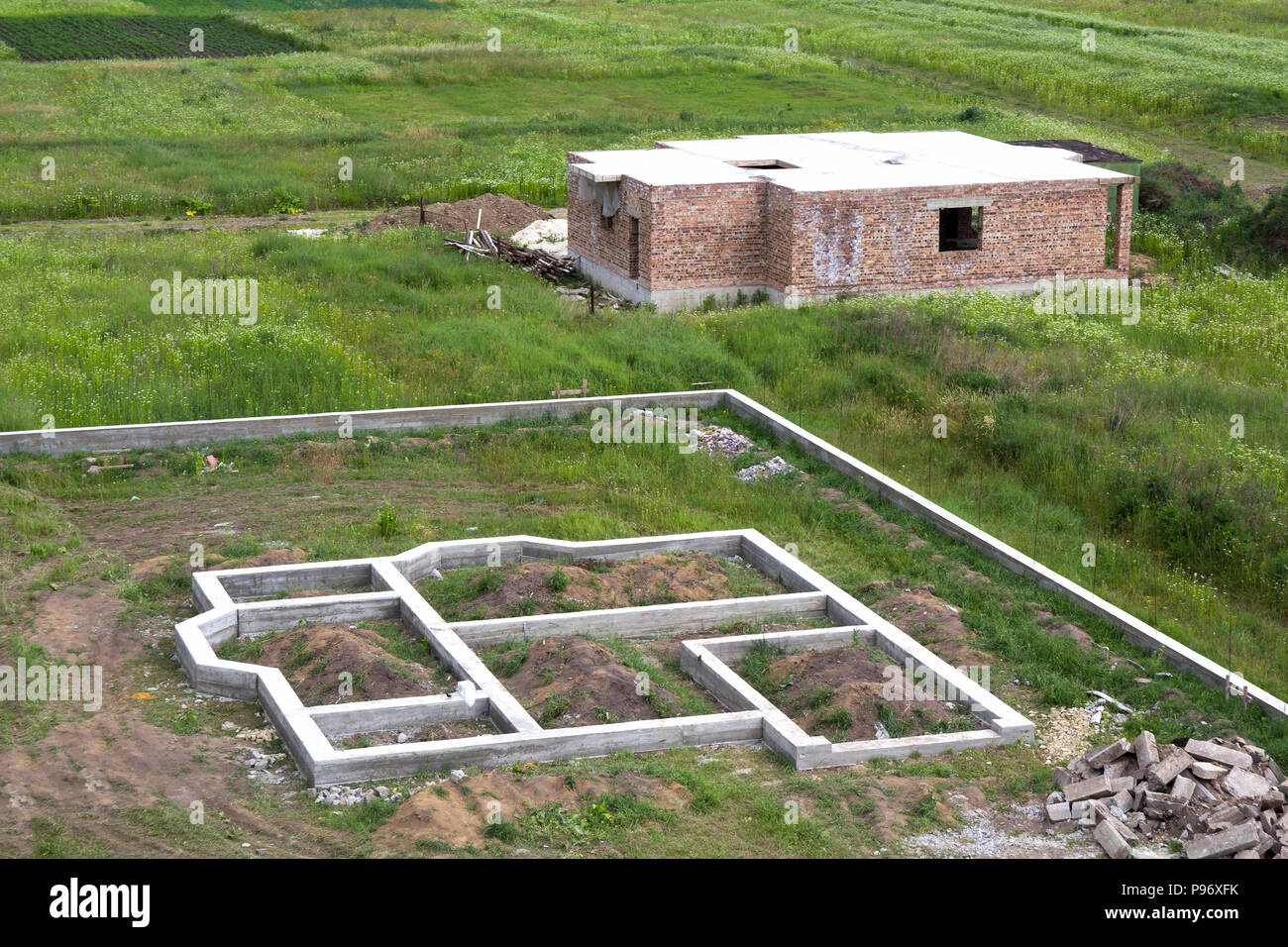 Building site in green field. Trenches dug in ground and filled with ...