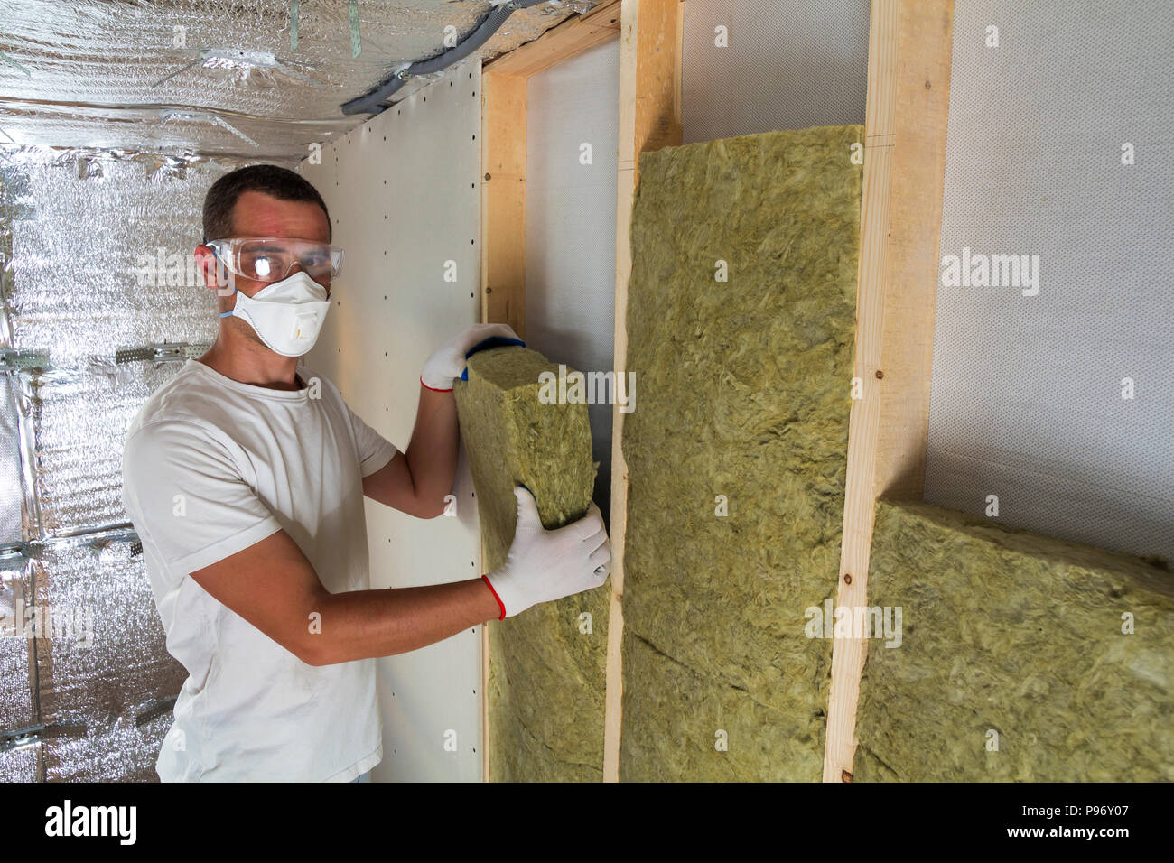 Young worker in respirator insulating rock wool insulation staff in ...