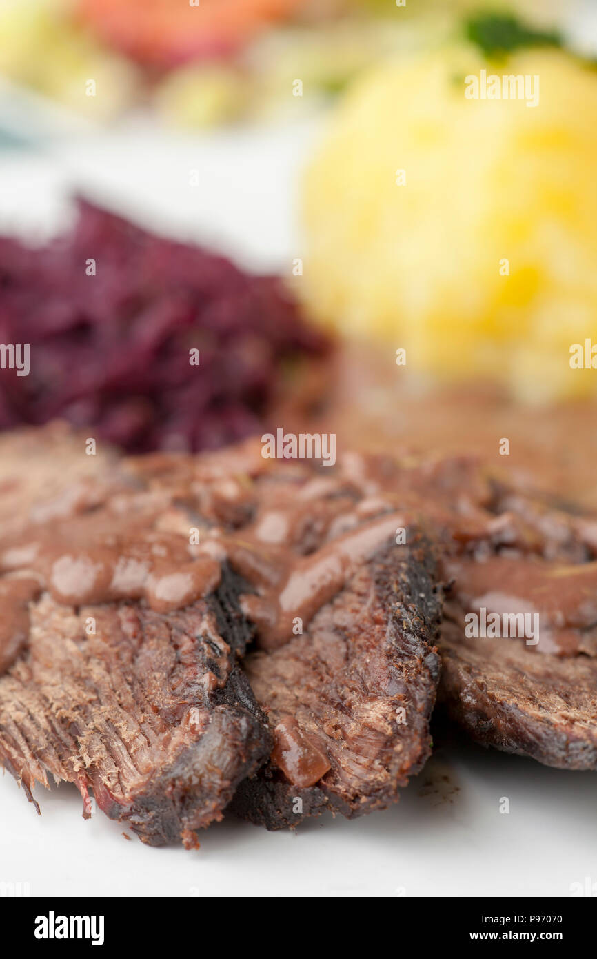 german sauerbraten with red cabbage on a plate Stock Photo - Alamy