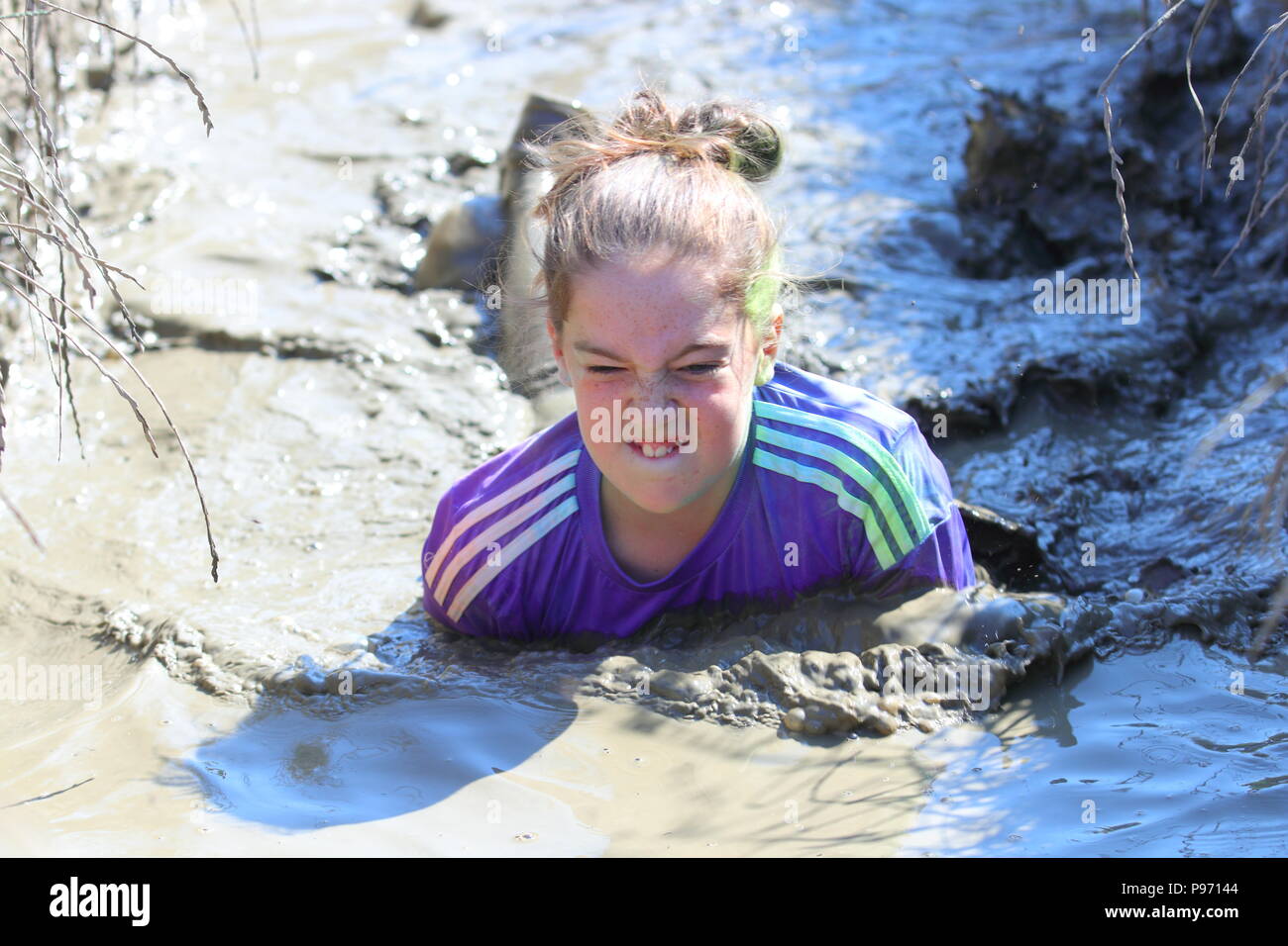 A young girl crawls through sludge during the Young Mudders Obstacle ...