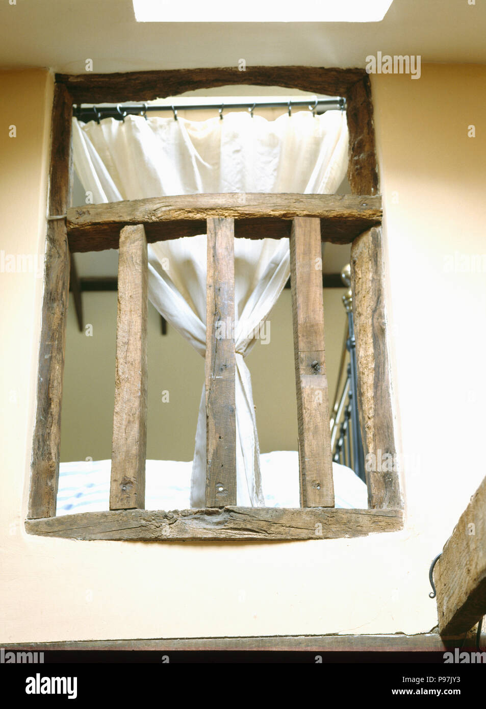 Cream curtain on rustic beamed window frame with view of attic bedroom ...