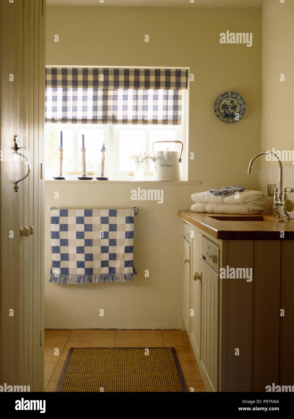 Blue and white checked blind on window above towel rail with a blue ...