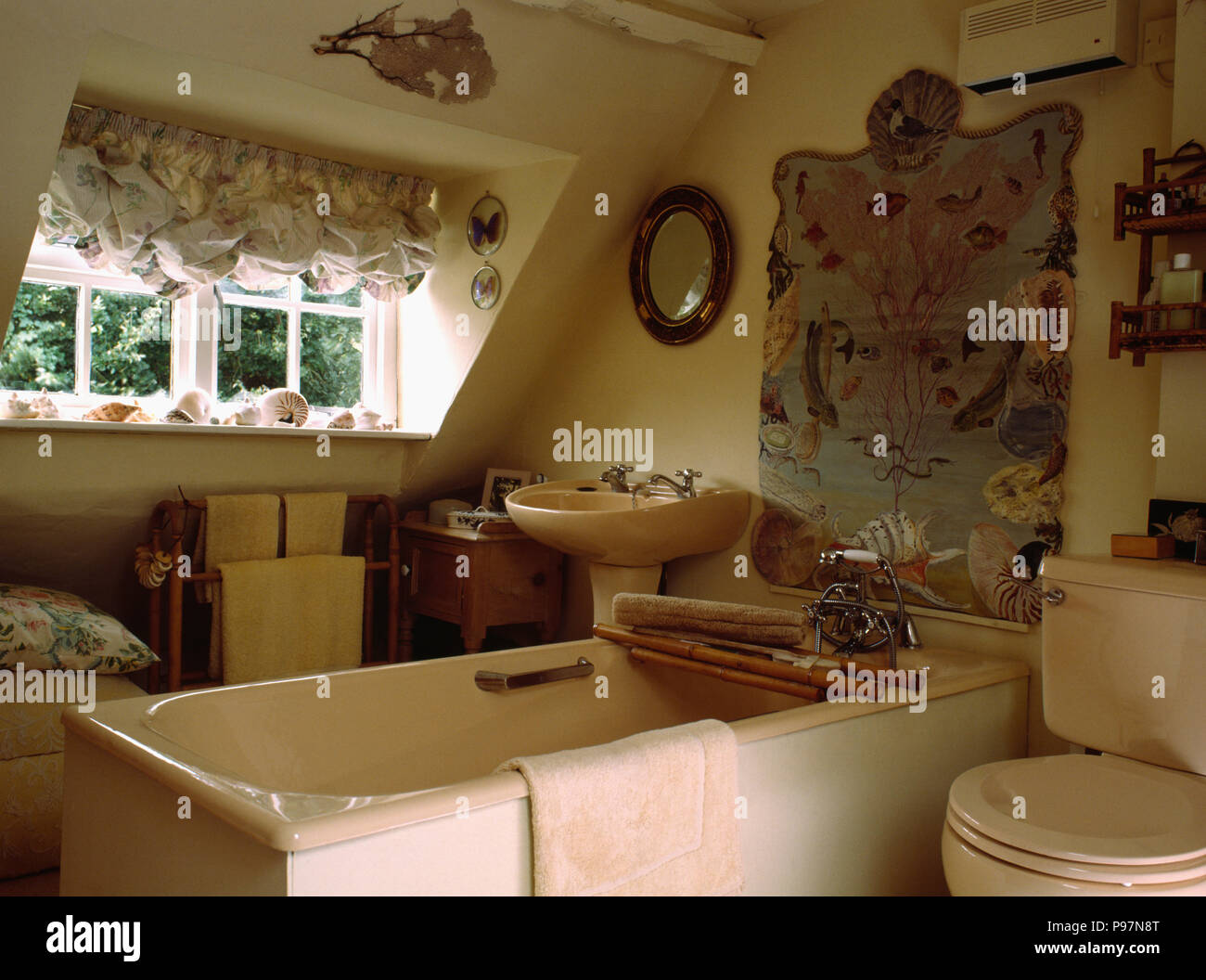 Pink bath and toilet in attic bathroom with festoon blinds at the ...