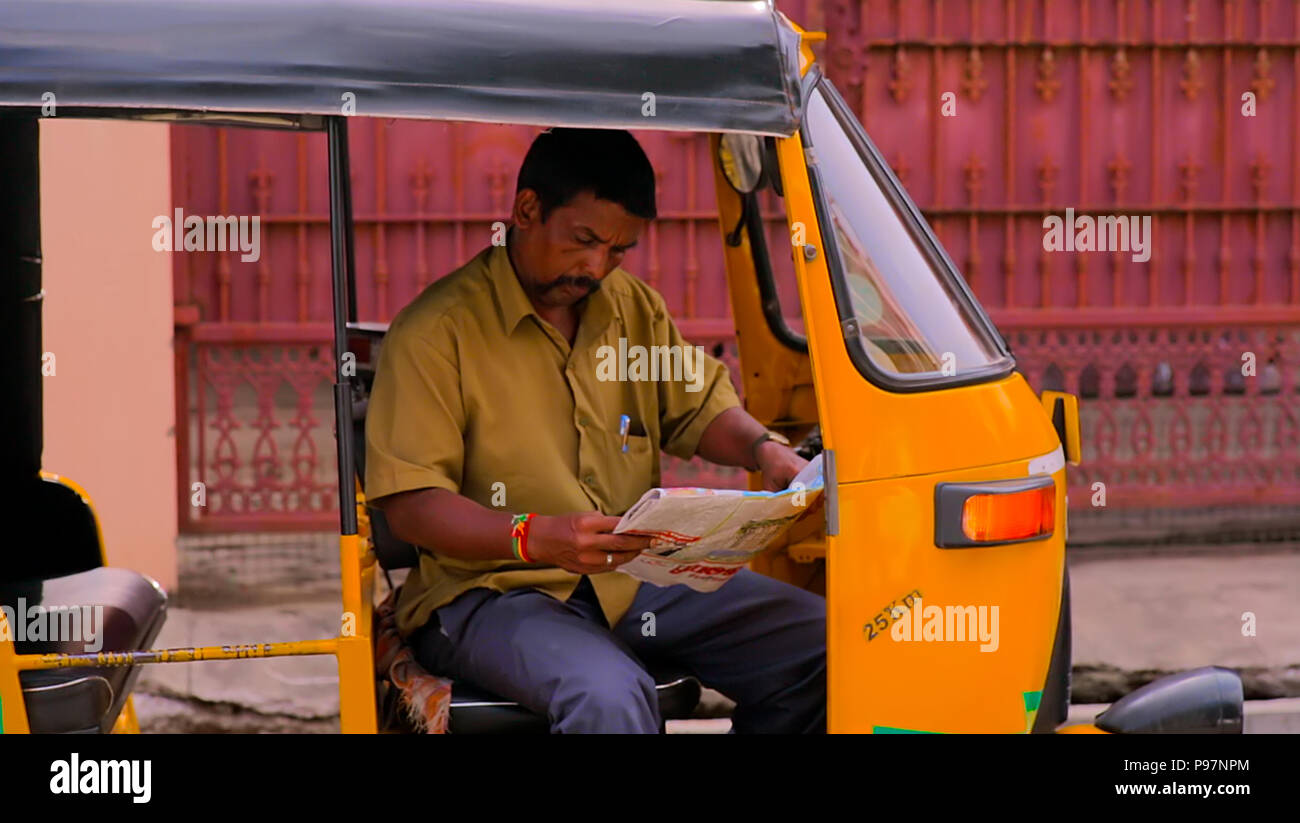 A auto rickshaw driver reading a newspaper in India Stock Photo - Alamy